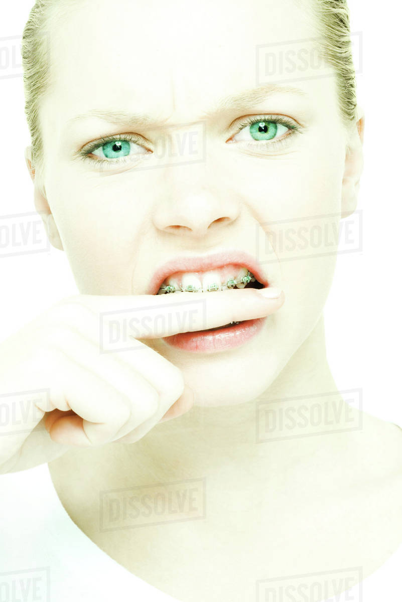 Teenage girl biting finger, close-up - Stock Photo - Dissolve