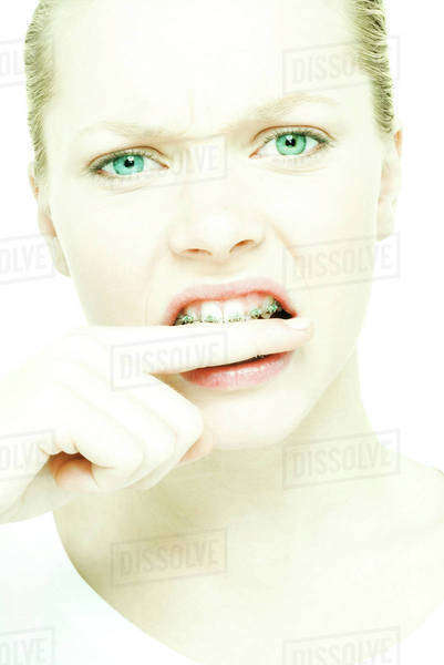 Teenage girl biting finger, close-up - Stock Photo - Dissolve