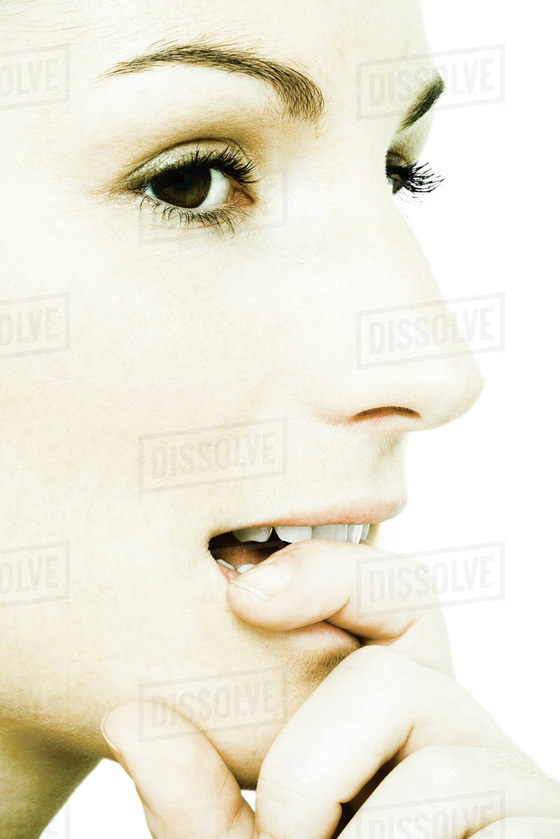 Young woman biting finger, extreme close-up - Stock Photo - Dissolve