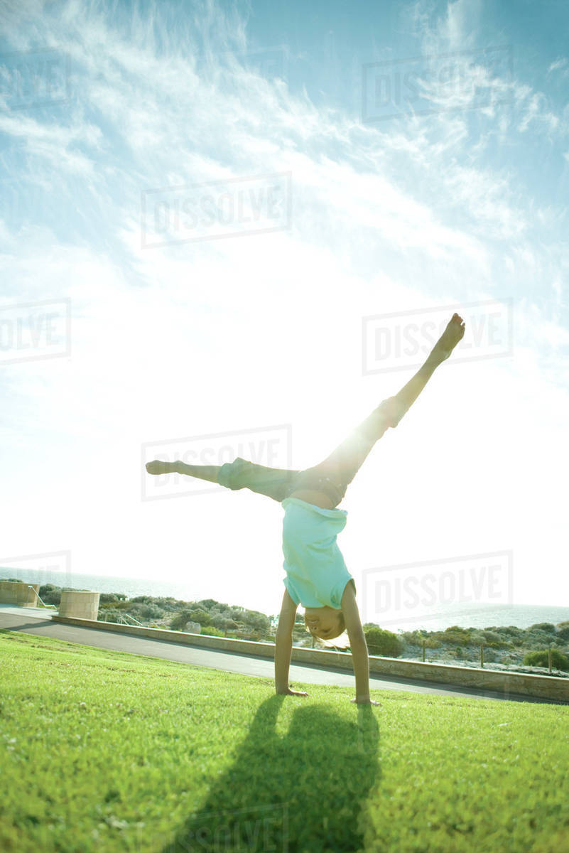 Girl doing cartwheel on grass - Royalty-free Stock Photo | Dissolve