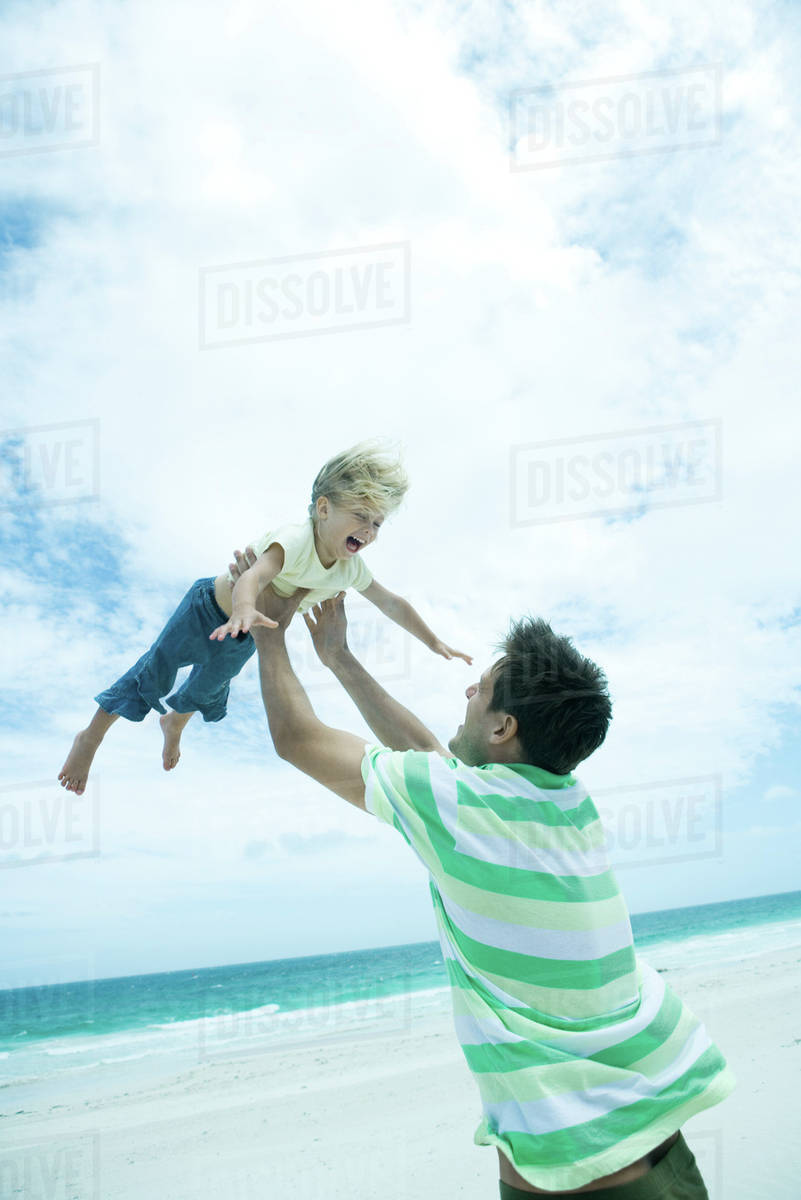 Man lifting child into air on beach - Stock Photo - Dissolve