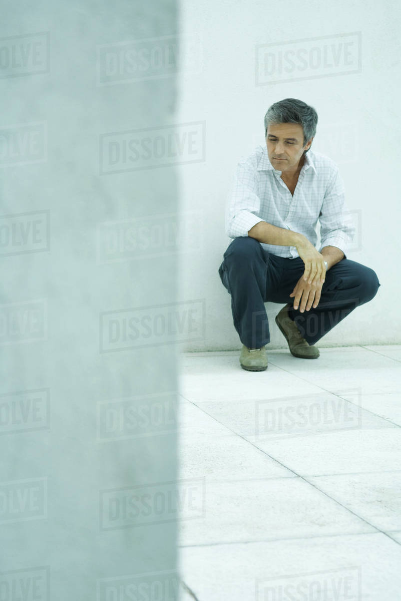 Mature man crouching, looking down, full length portrait - Stock Photo ...