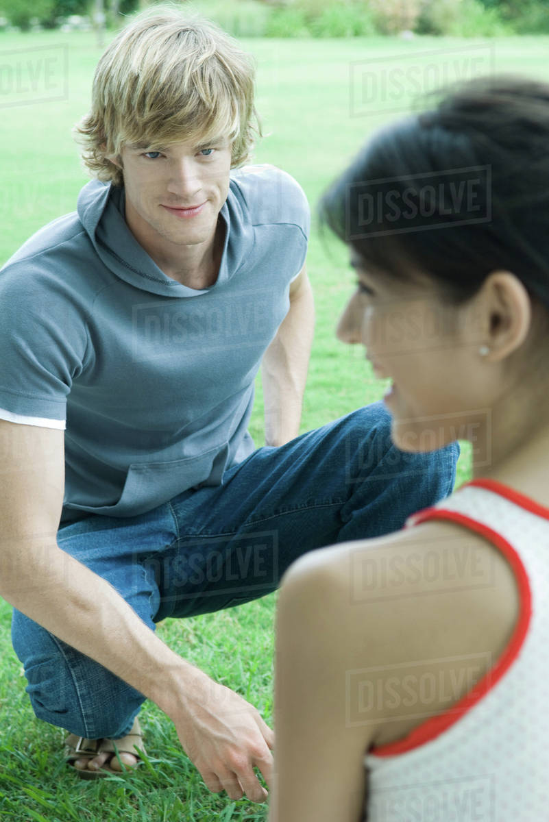 Young man and woman, man crouching on lawn looking at woman - Royalty ...