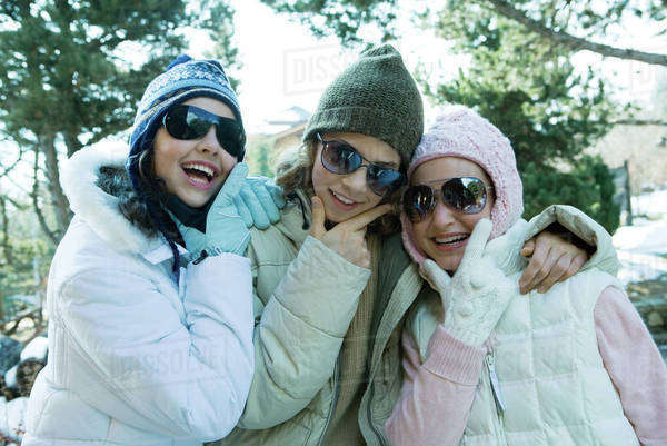 Three teen girls wearing winter clothes and sunglasses, holding chins ...