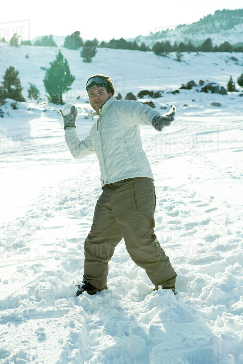 Young man throwing snowball, smiling at camera, full length - Stock ...