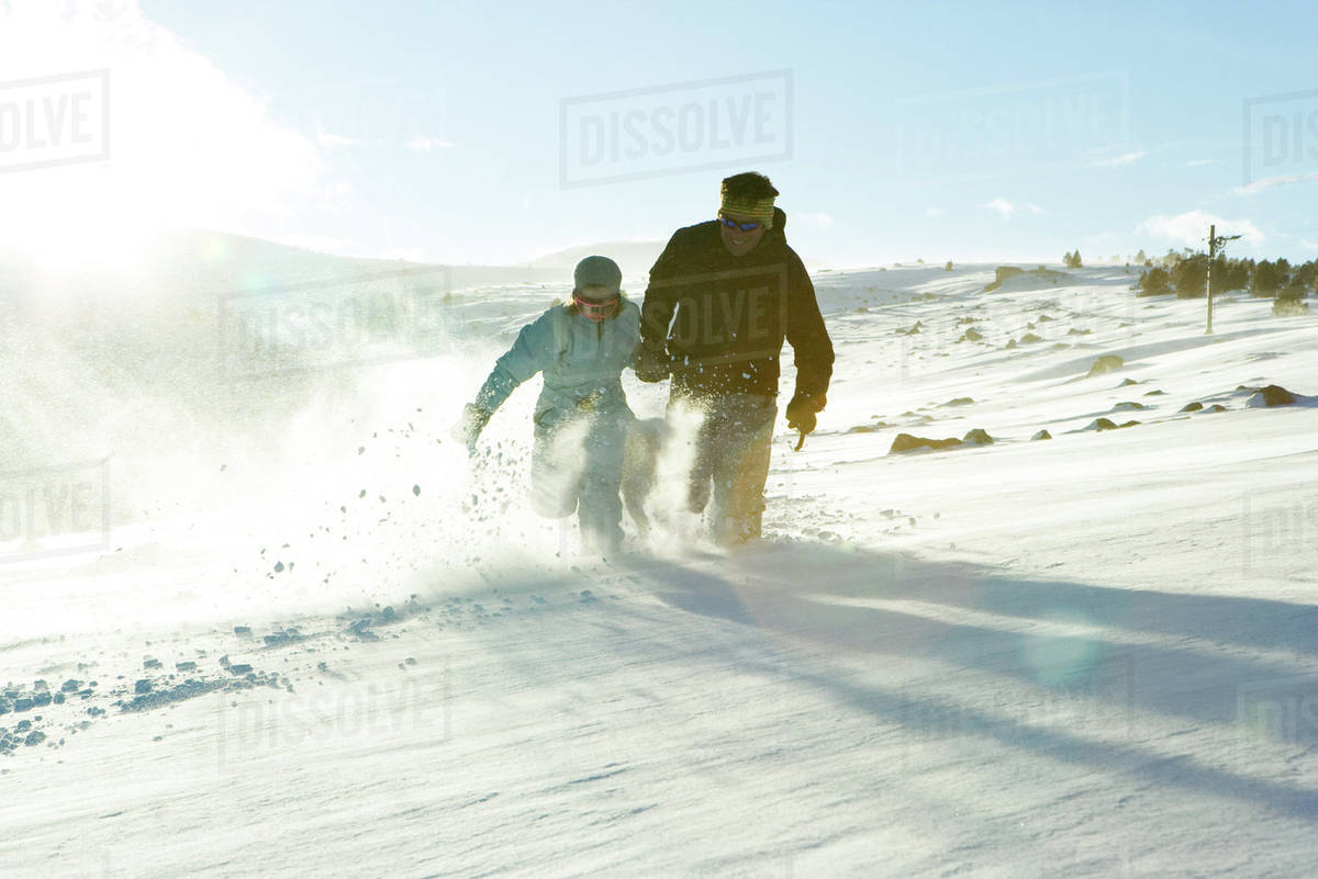 Father and daughter running in snow together, full length - Stock Photo ...