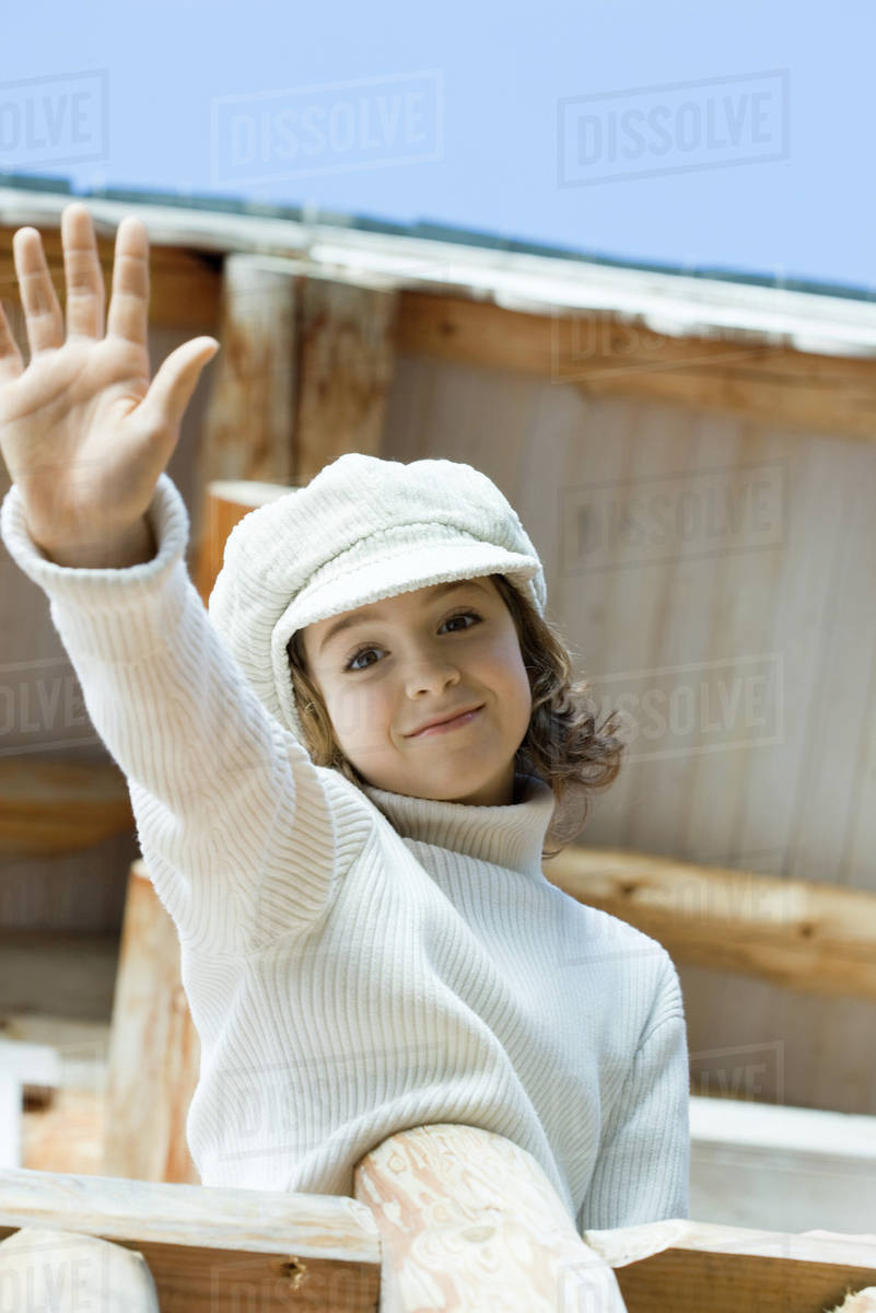 Girl waving to camera from deck of chalet, low angle view - Royalty ...