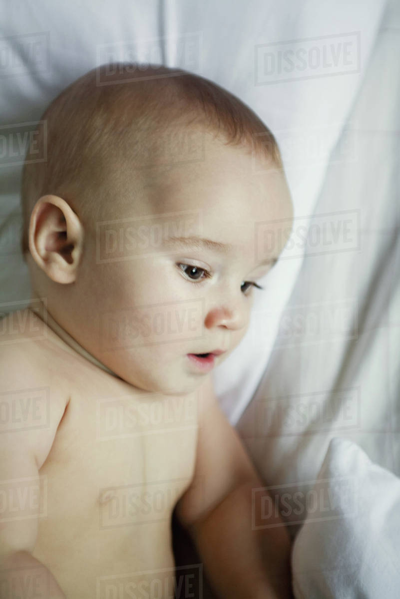 Baby in bed, looking down, close-up - Royalty-free Stock Photo | Dissolve