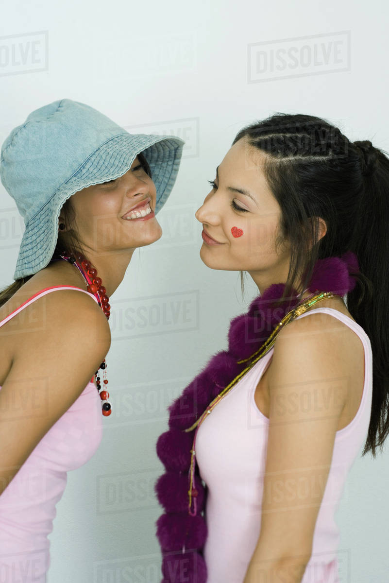 Two young friends standing face to face, smiling at each other ...