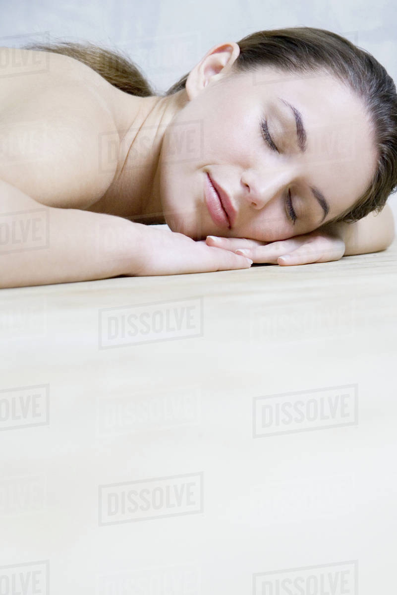 Young woman resting head on arms, eyes closed, cropped view - Royalty ...