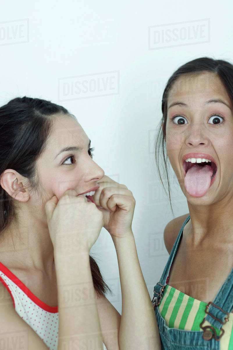Two young female friends making faces, portrait - Stock Photo - Dissolve