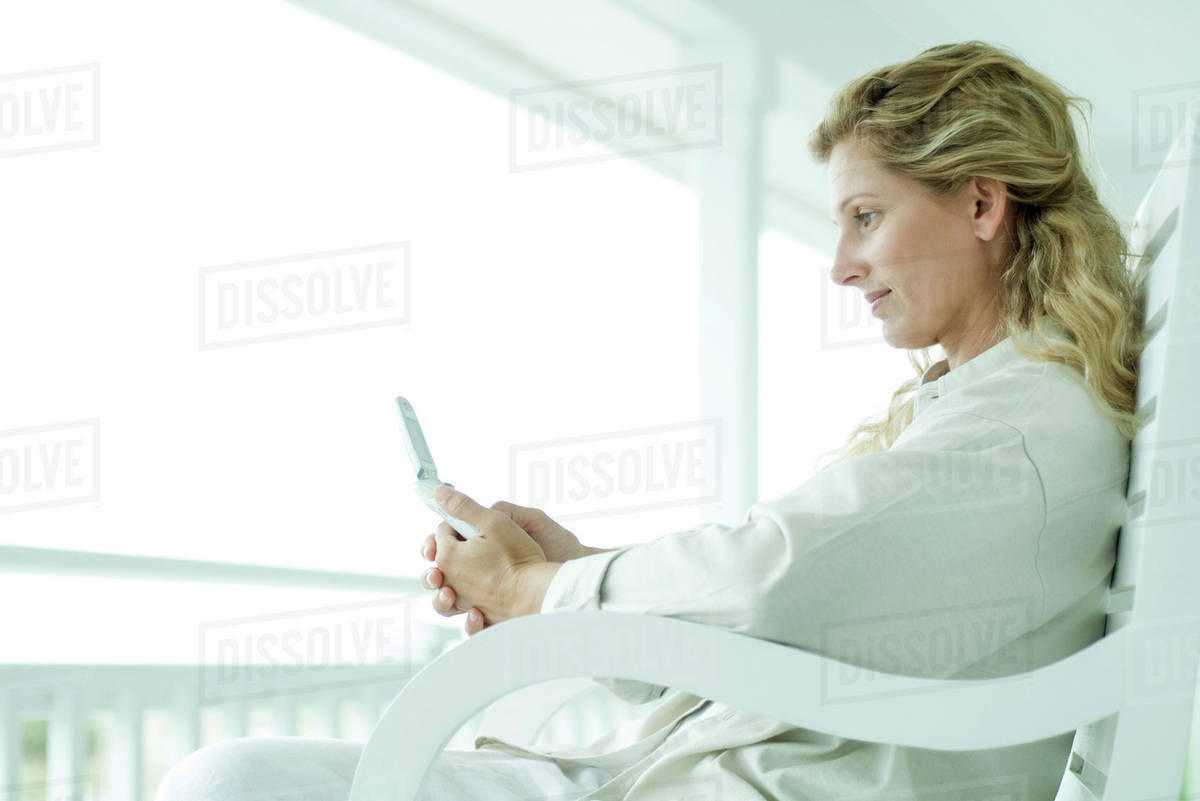 Woman sitting on porch, looking at cell phone, profile - Royalty-free ...