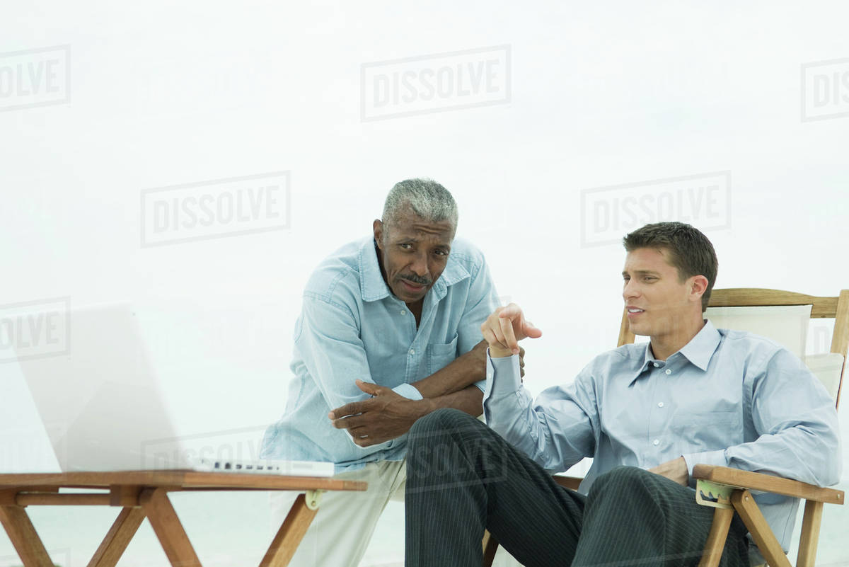 Two men looking at laptop together, outdoors - Royalty-free Stock Photo ...