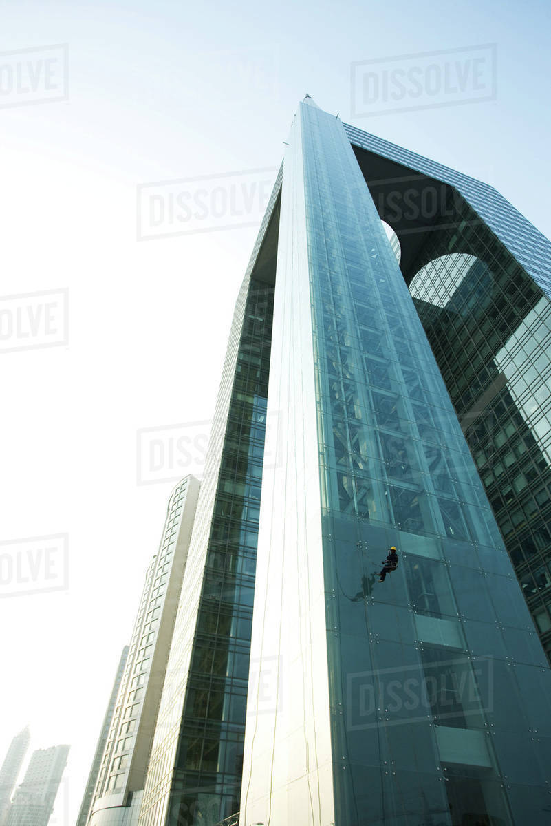 Window washer on side of skyscraper, low angle view - Stock Photo ...