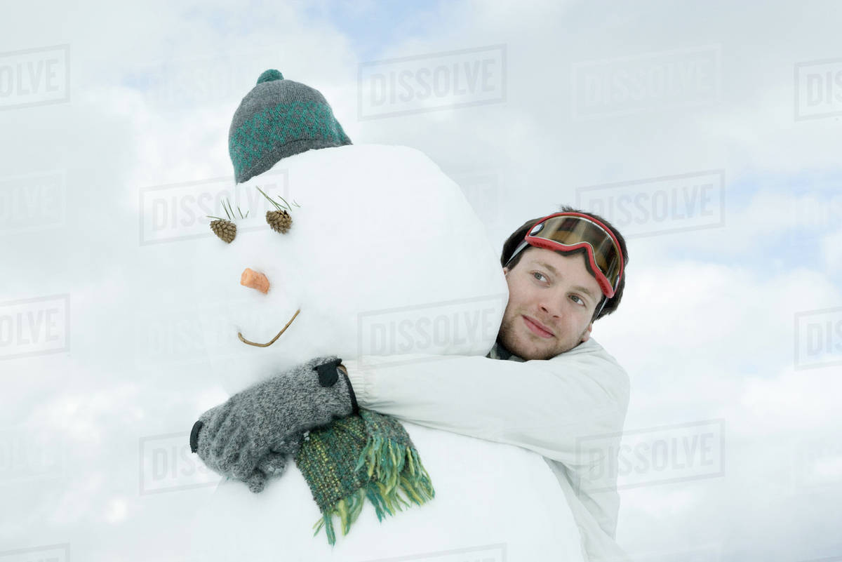 Young man hugging snowman - Royalty-free Stock Photo | Dissolve