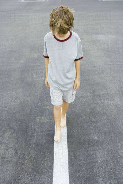 Boy walking along white dividing line, high angle view - Royalty-free ...