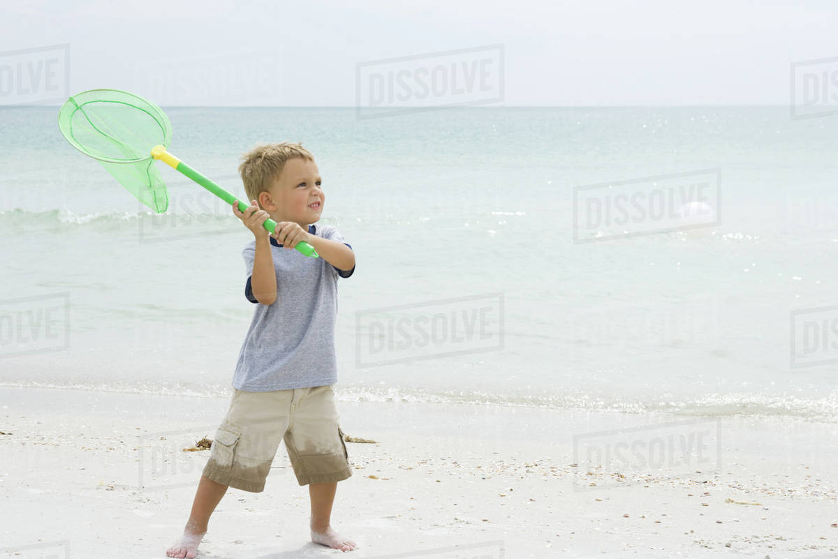 Young boy at the beach, holding up net to catch ball - Royalty-free ...
