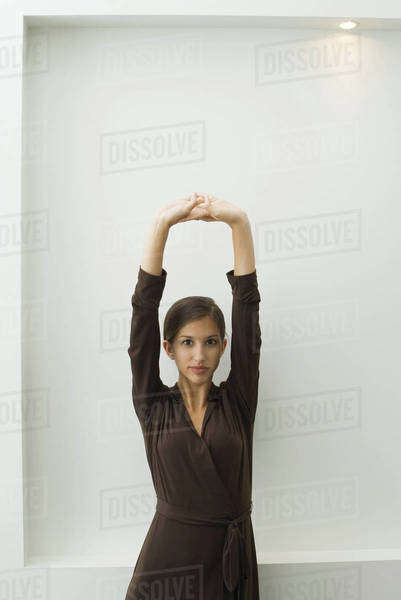 Teenage girl standing with arms raised, clasped hands, looking at ...