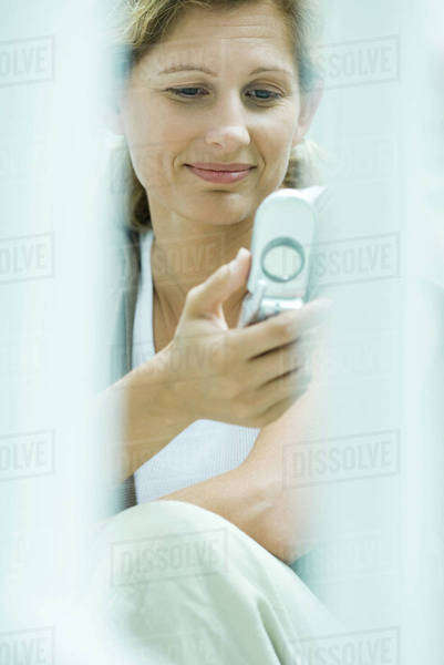 Woman holding up cell phone, smiling, selective focus - Royalty-free ...