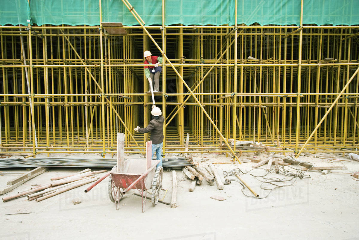 Two workers assembling scaffolding on construction site - Royalty-free ...