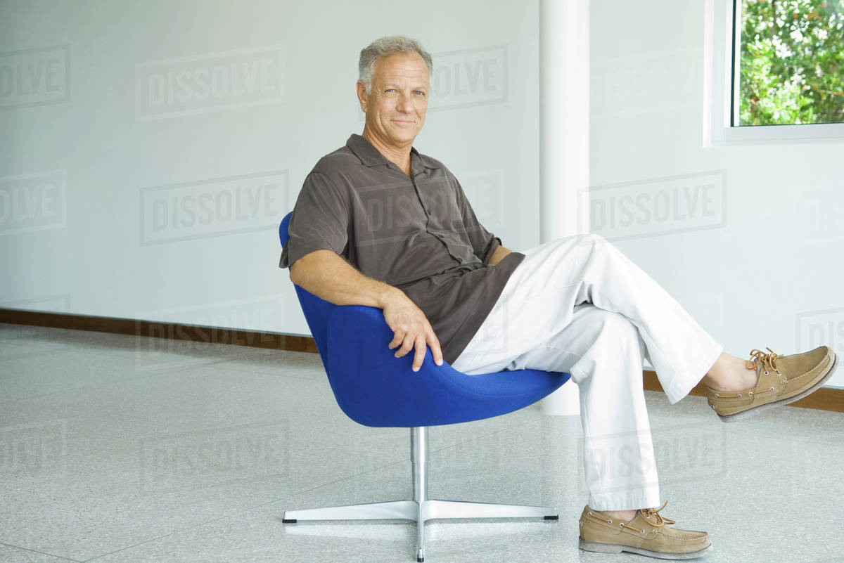 Mature man sitting in chair, full length, portrait - Stock Photo - Dissolve