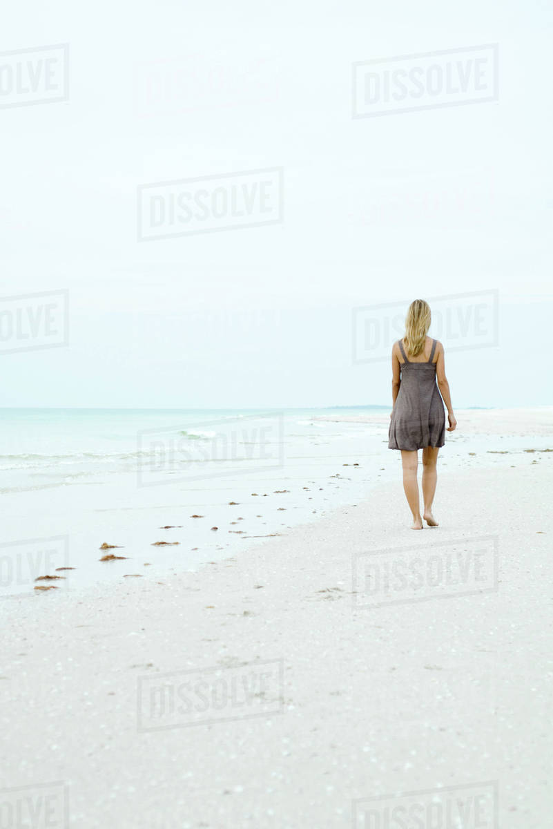 Woman in sundress walking at the beach, rear view - Royalty-free Stock ...