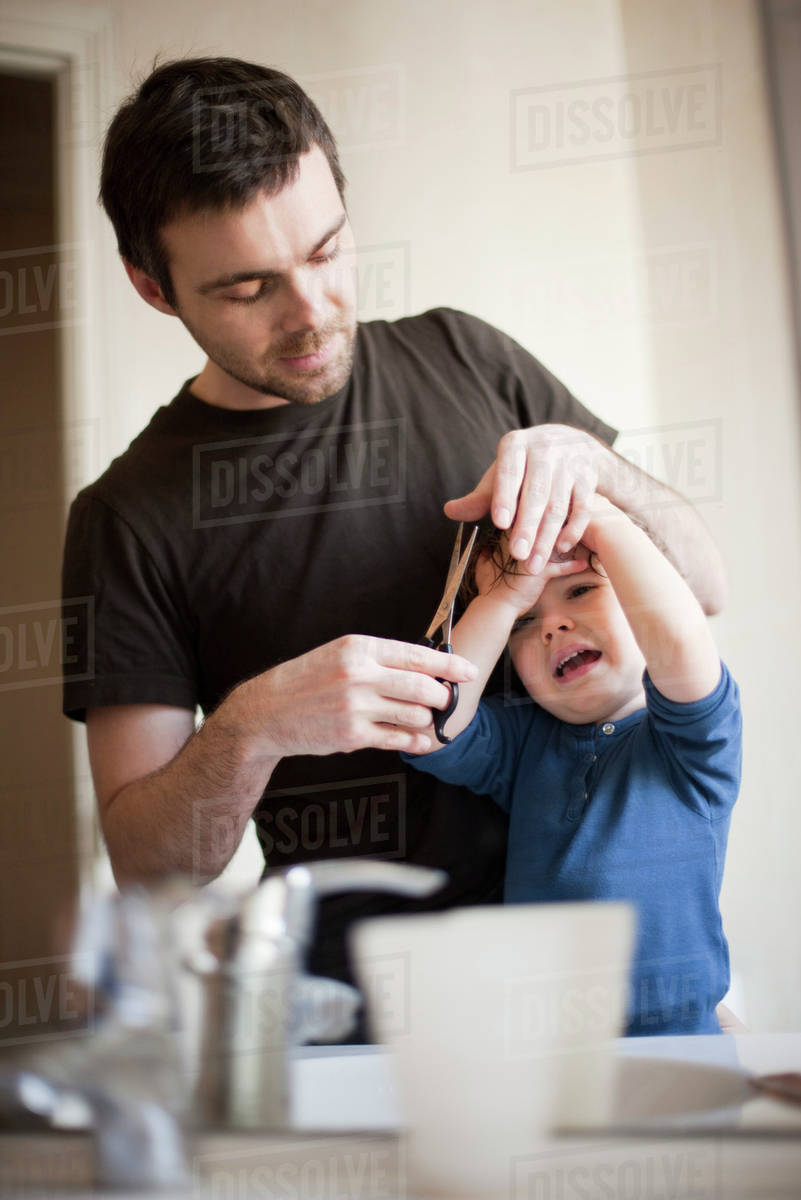 Father giving crying child a haircut - Royalty-free Stock Photo | Dissolve