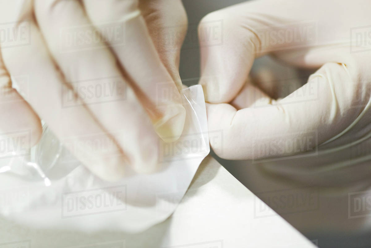 Healthcare worker wearing latex gloves, opening sterile package ...