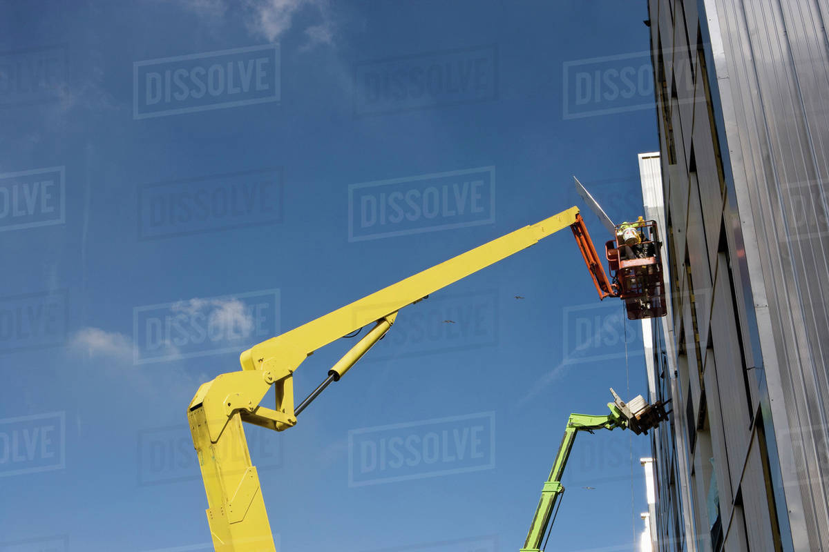 Construction workers in cherry picker bucket working on building ...