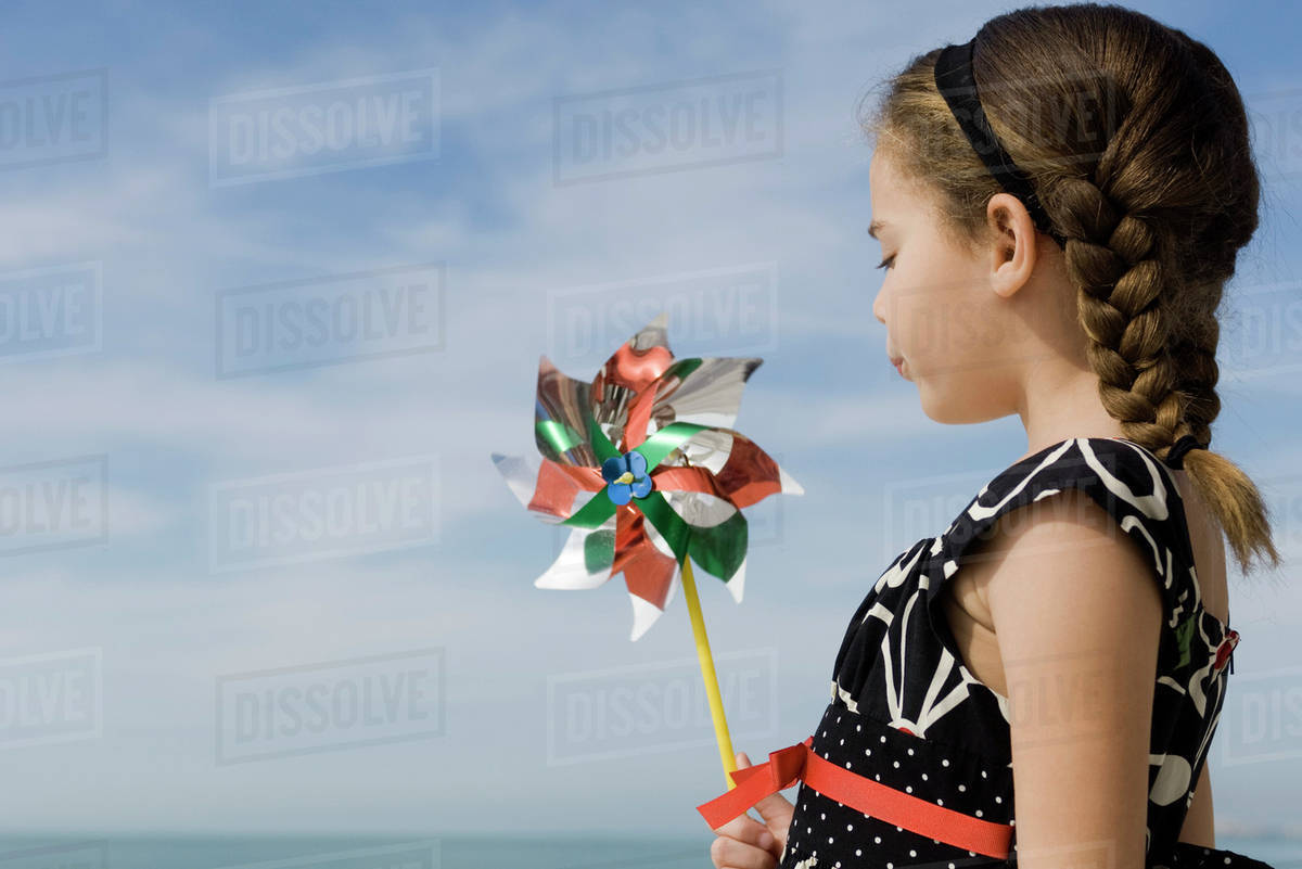 Little girl blowing pinwheel - Stock Photo - Dissolve