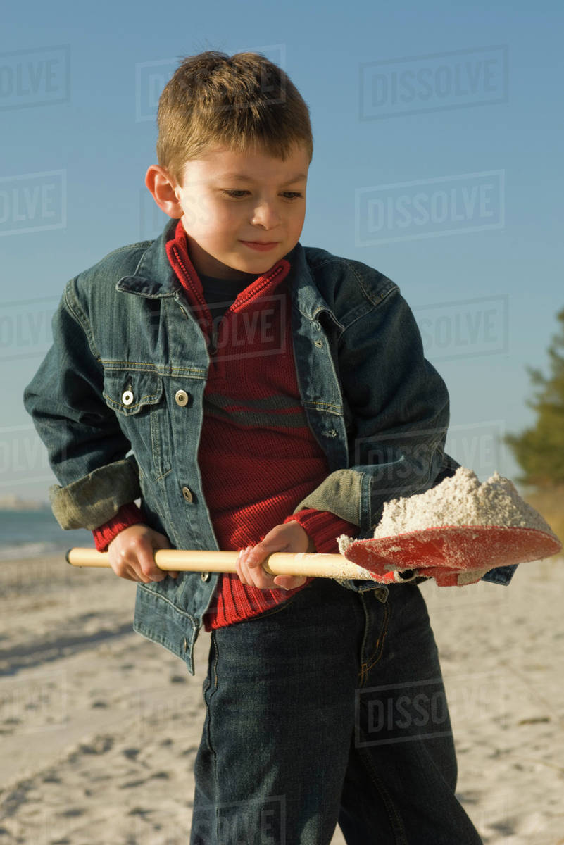 Boy digging with shovel on sandy beach - Royalty-free Stock Photo ...