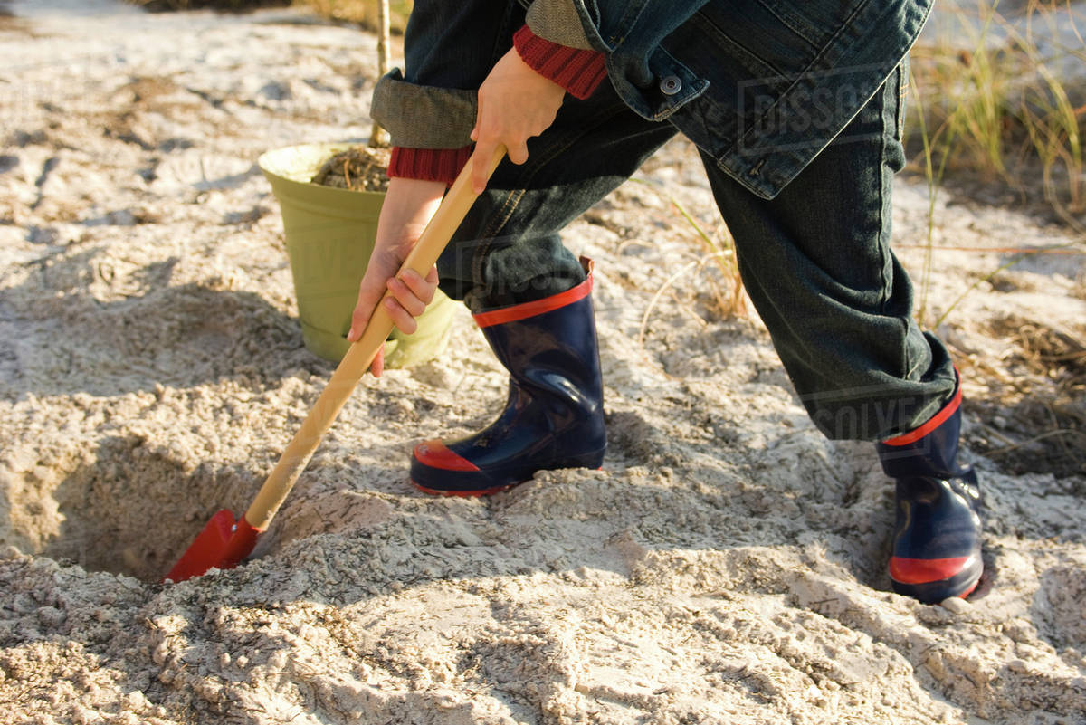Boy digging hole in sand - Royalty-free Stock Photo | Dissolve