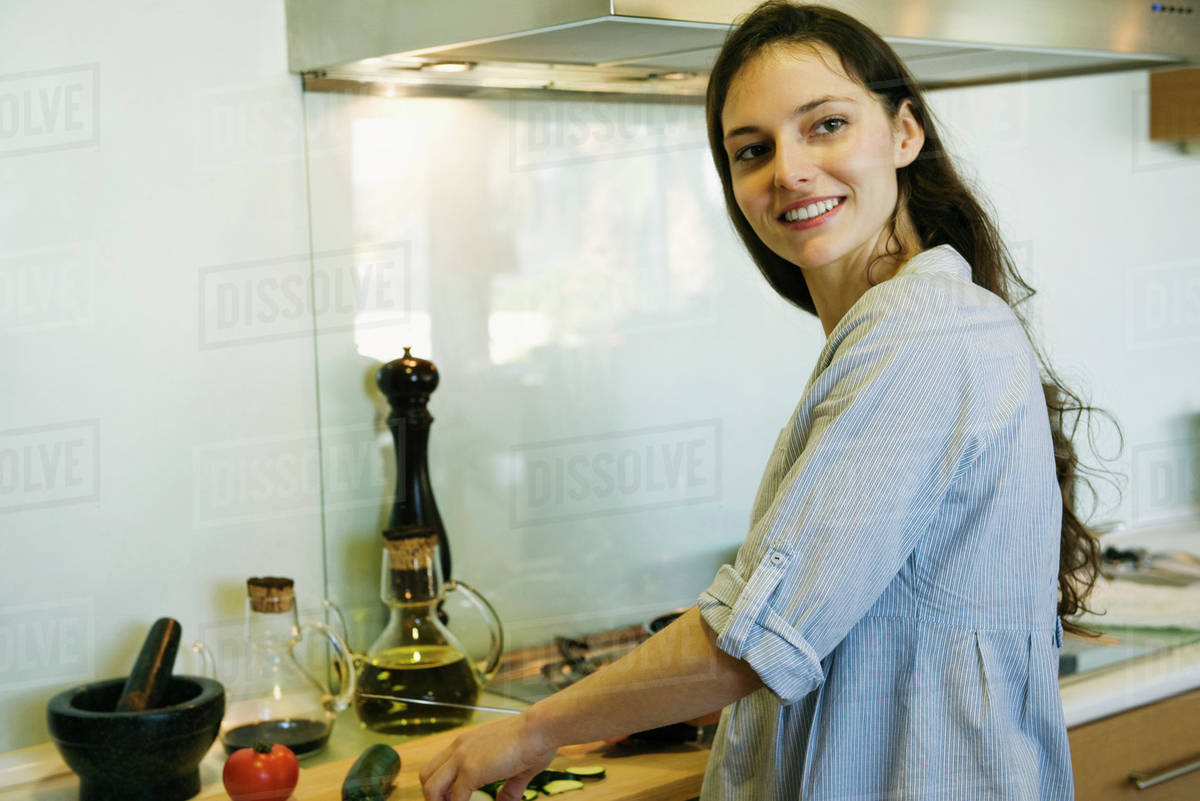 Woman cooking, smiling over shoulder, portrait - Stock Photo - Dissolve