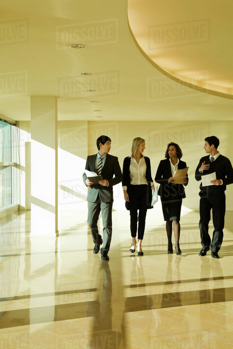 Group of executives talking as they walk together in lobby - Royalty ...