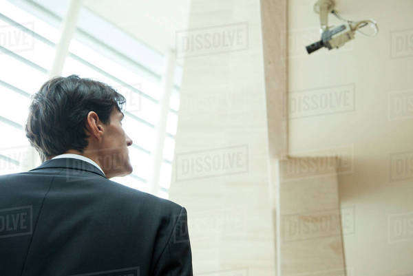 Businessman looking up at security camera - Royalty-free Stock Photo ...