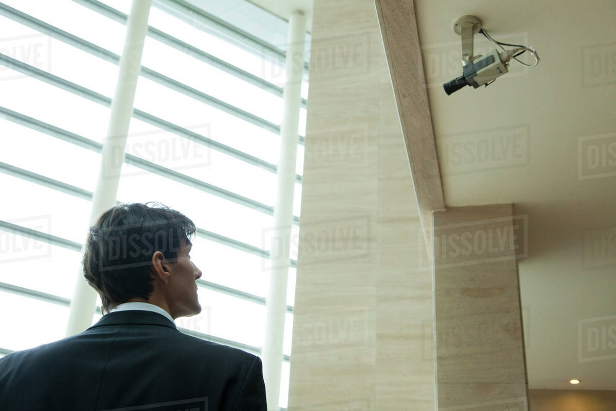 Businessman looking up at security camera - Royalty-free Stock Photo ...