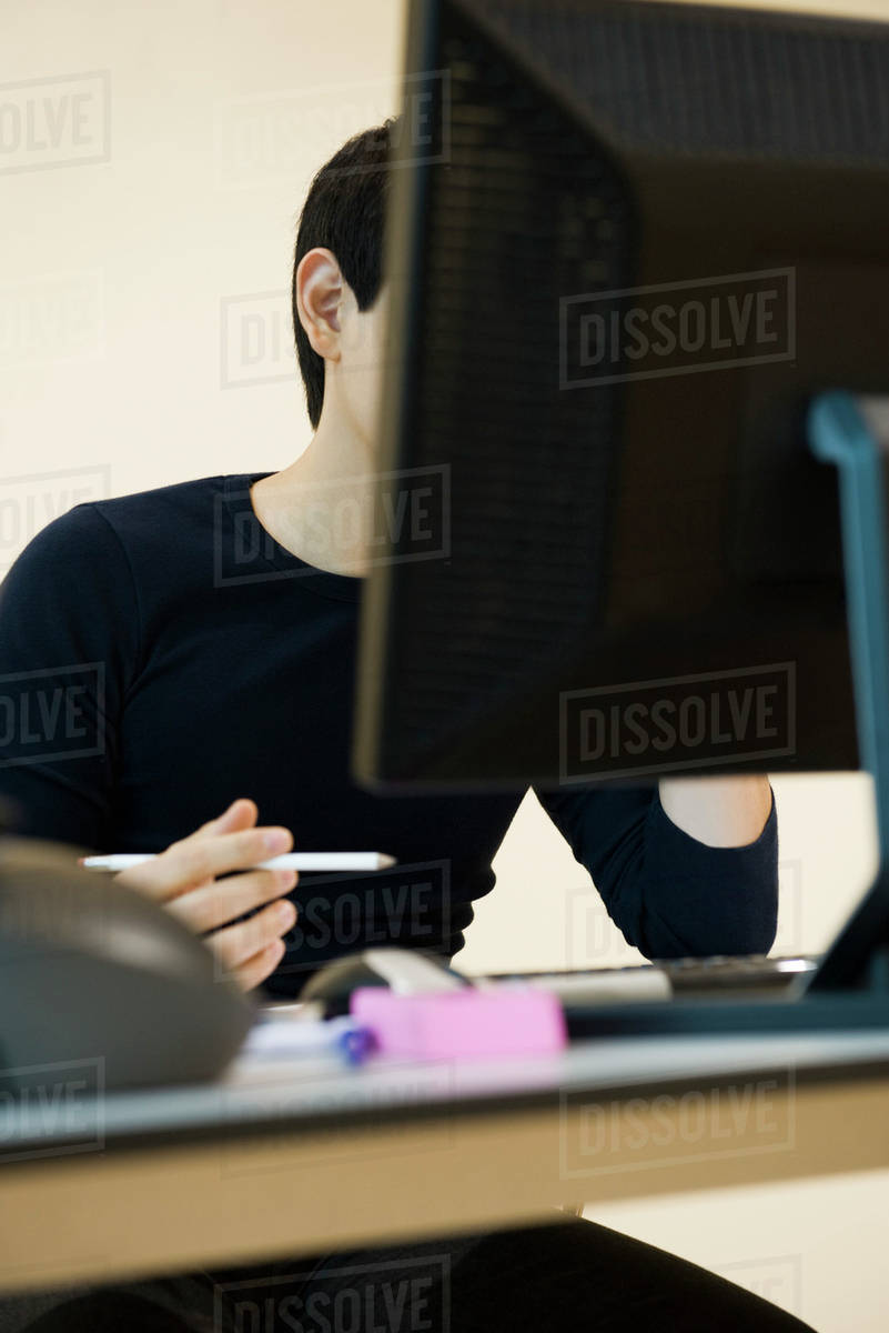 Office worker sitting at desk with computer - Stock Photo - Dissolve