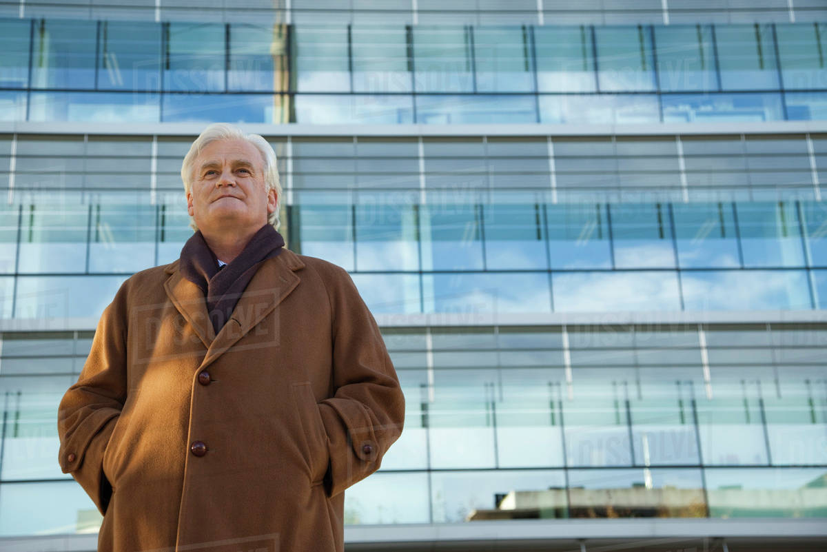 Mature man standing in front of building, looking away, portrait ...