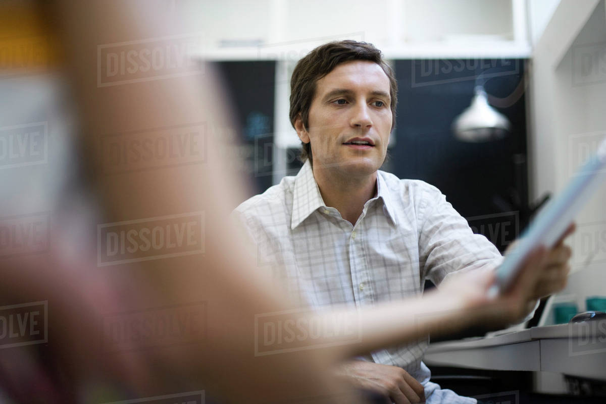 Man receiving document from colleague - Royalty-free Stock Photo | Dissolve