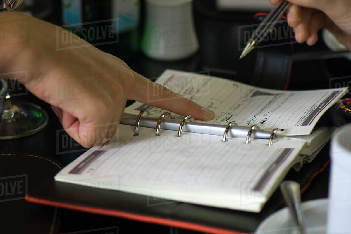 Two people making plans using agenda, one holding pen while the other ...