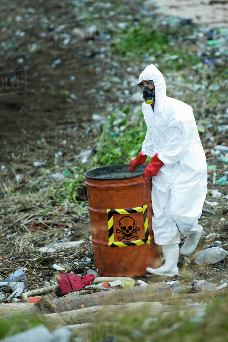 Person in protective suit carrying barrel of hazardous waste - Royalty ...