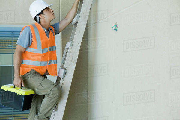 Man climbing ladder carrying toolbox - Stock Photo - Dissolve