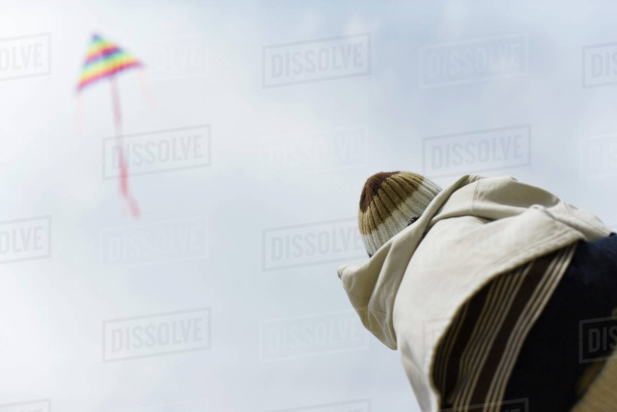 Child watching kite in sky, rear view - Royalty-free Stock Photo | Dissolve