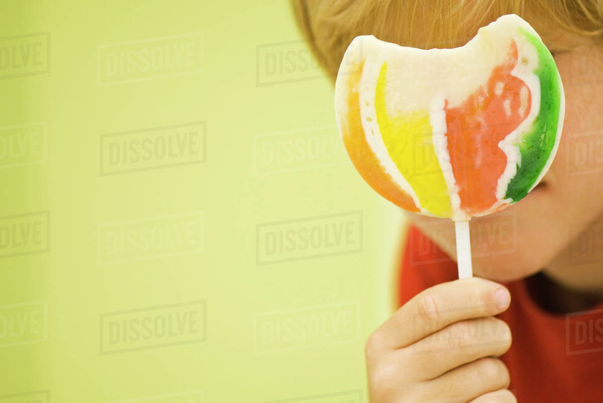 Child holding up lollipop - Royalty-free Stock Photo | Dissolve