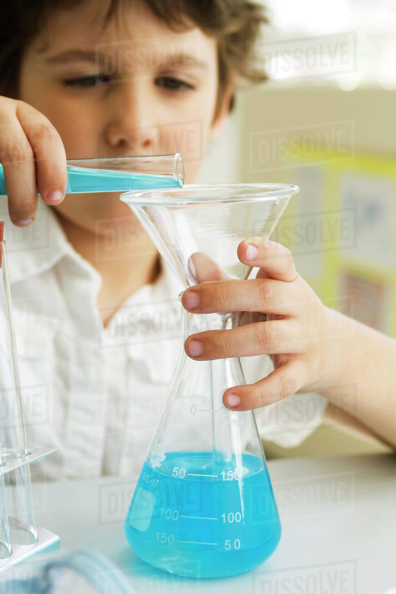 Boy transferring liquid from test tube to beaker using funnel - Royalty ...