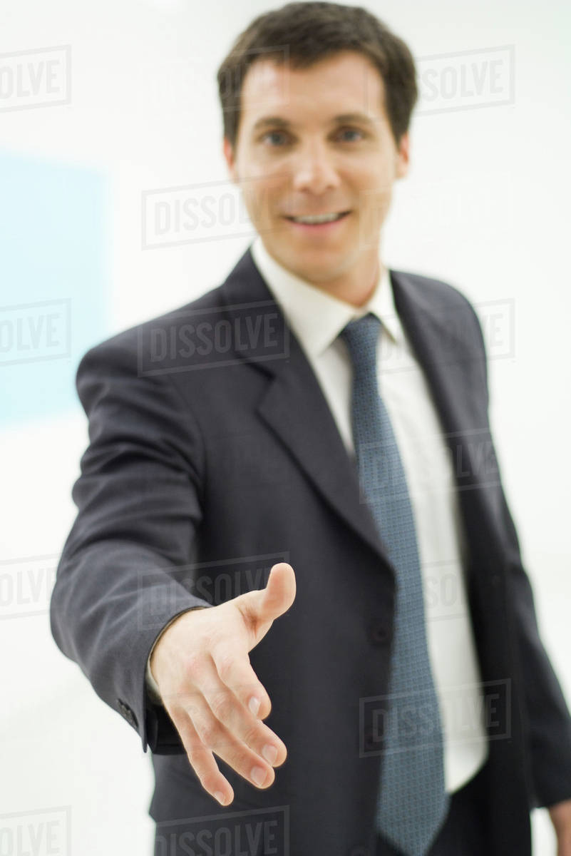 Businessman holding hand out toward camera, smiling, personal ...