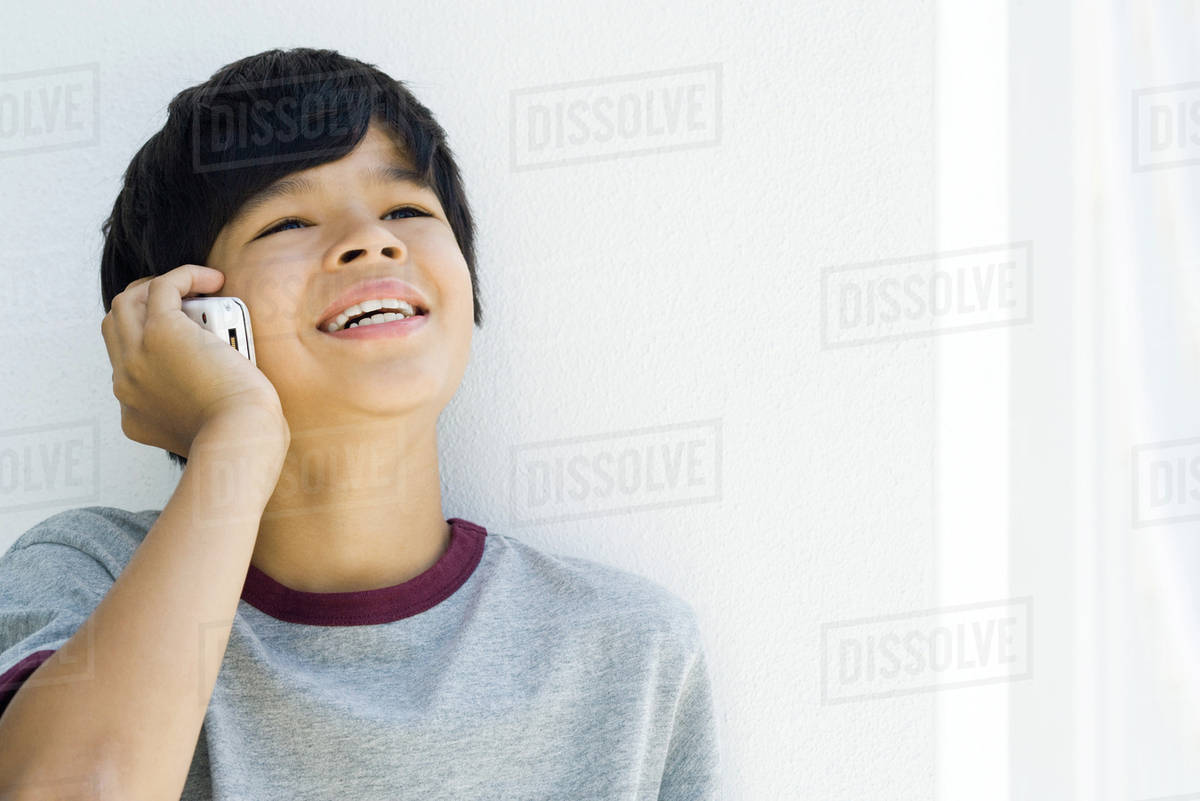 Boy using cell phone, looking up, smiling - Royalty-free Stock Photo ...
