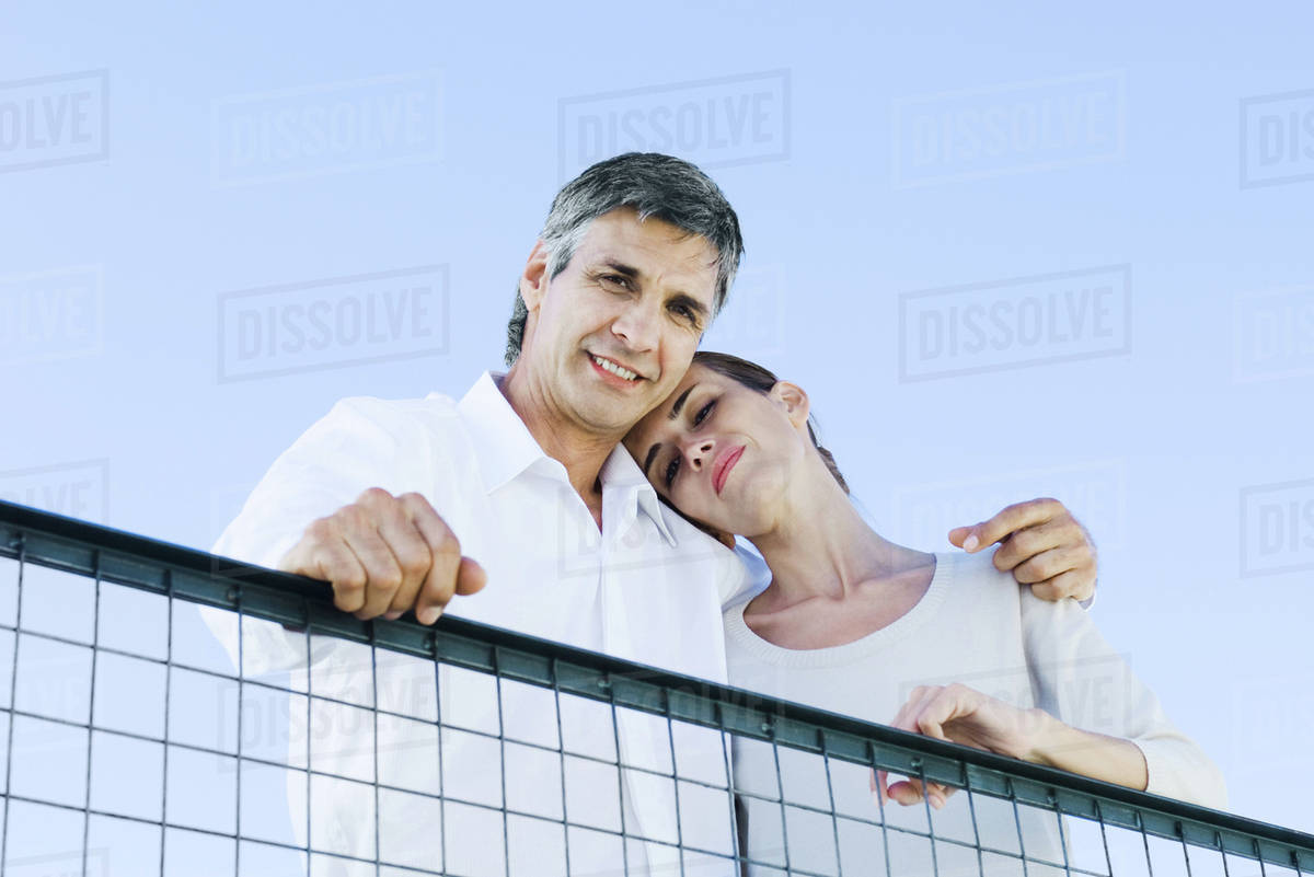 Couple looking down over wire fence at camera, low angle view - Royalty ...