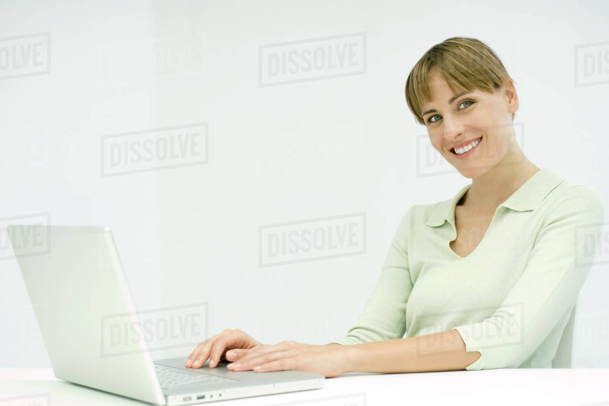Woman using laptop computer, smiling at camera - Royalty-free Stock ...