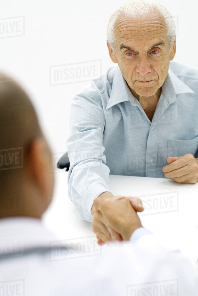 Senior man shaking younger man's hand, over the shoulder view - Stock ...